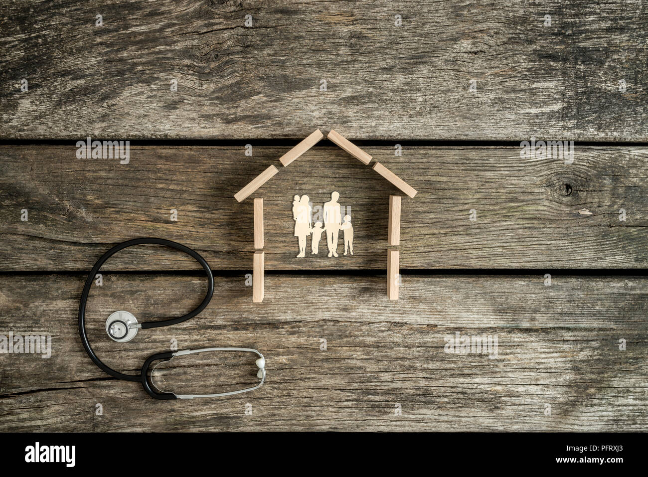 Cut outs of a young family with kids in a house with a stethoscope ...