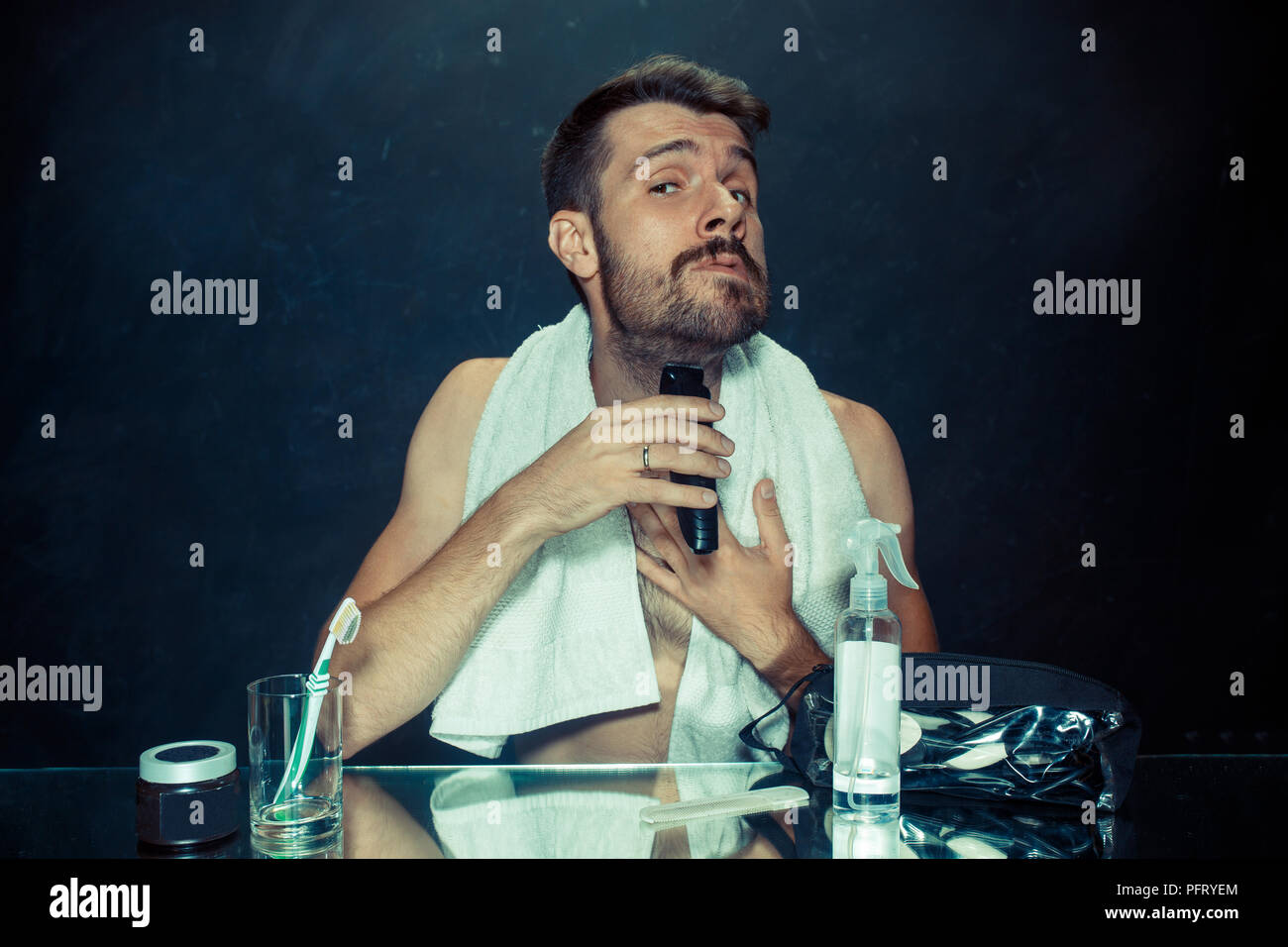 The young man in bedroom sitting in front of the mirror scratching his ...