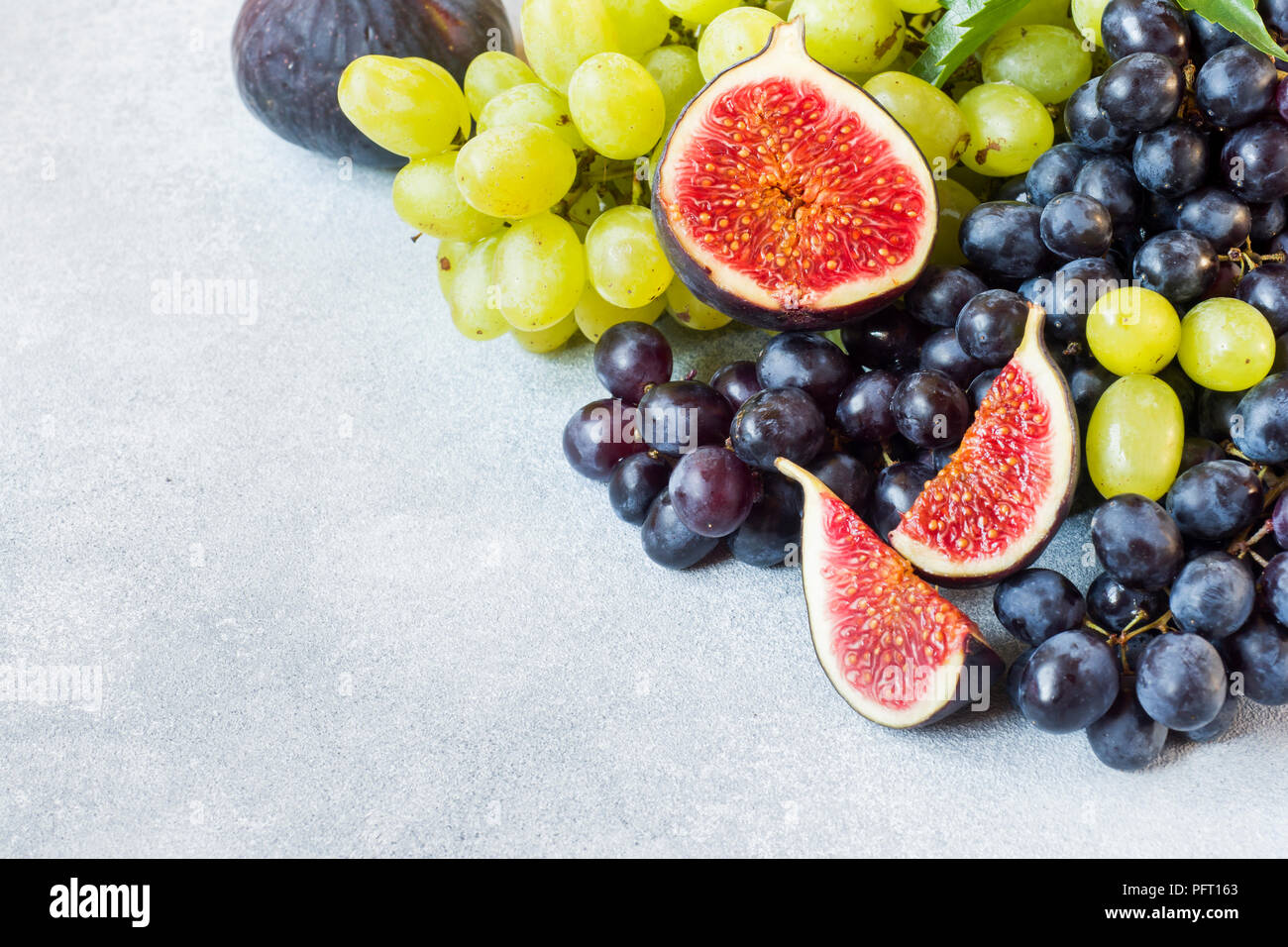 Still life of fresh autumn fruit. Grapes black and green, figs and ...