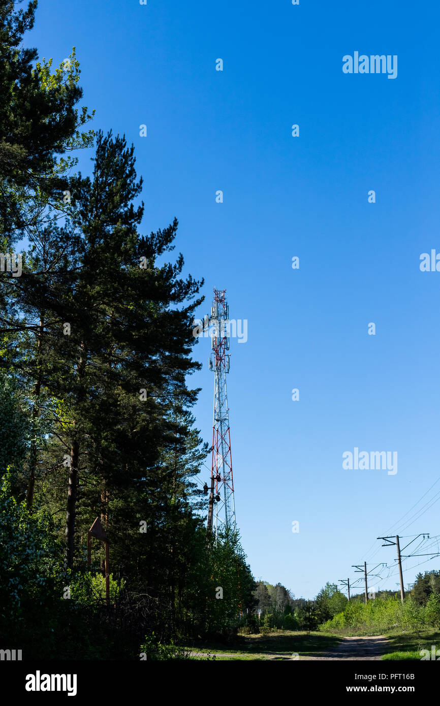 Huge communication antenna tower and satellite dishes against blue sky ...