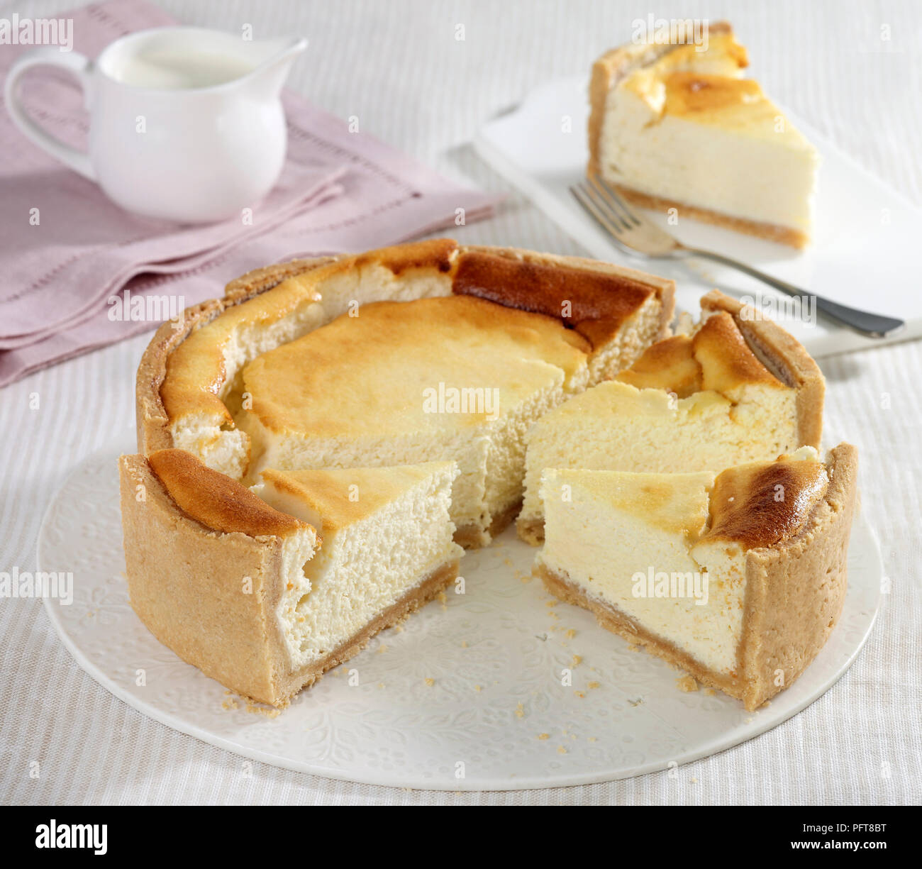 German quark cheesecake served on platter with fork and jug of cream ...