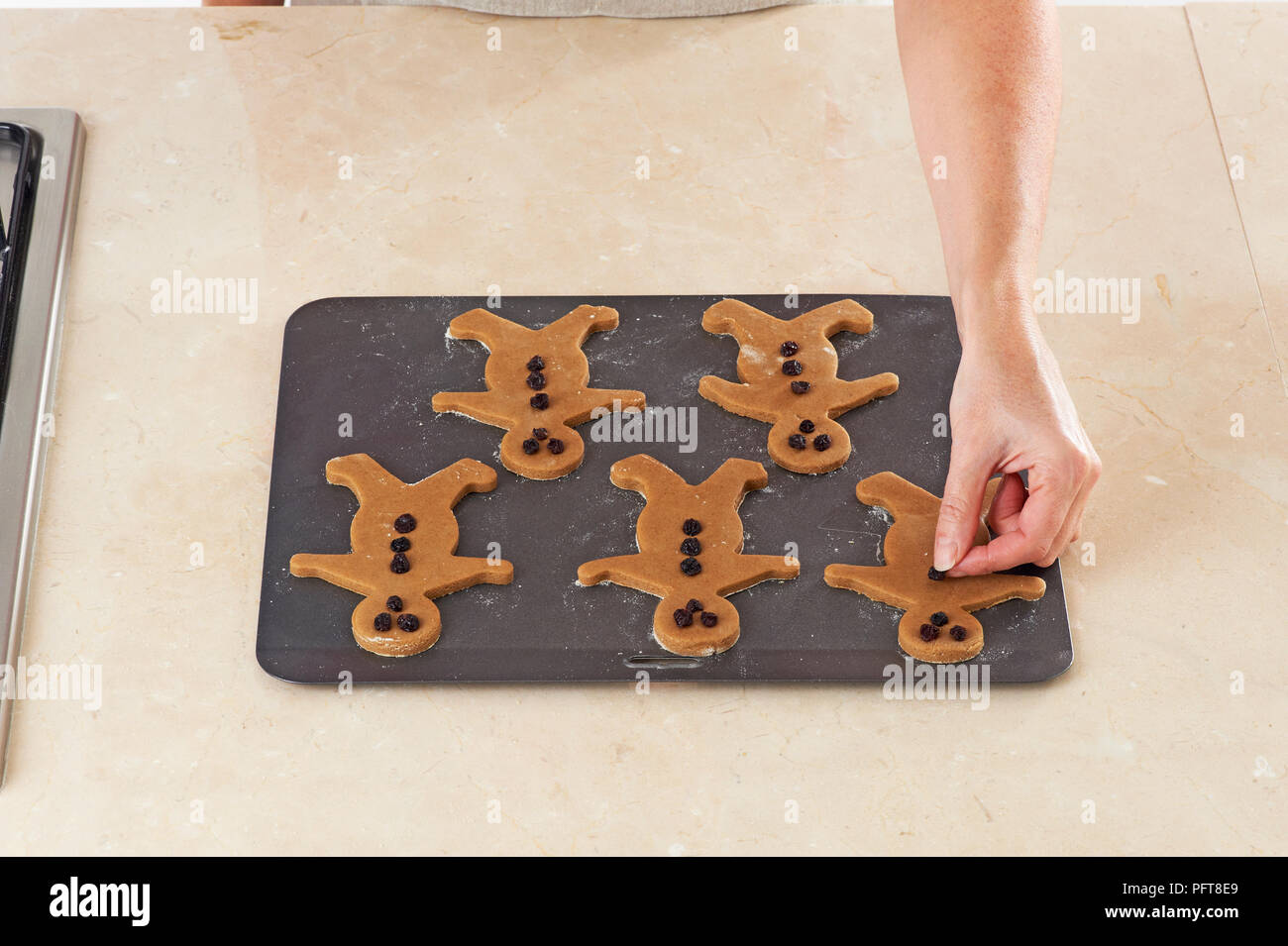Decorating gingerbread men using chocolate buttons Stock Photo - Alamy