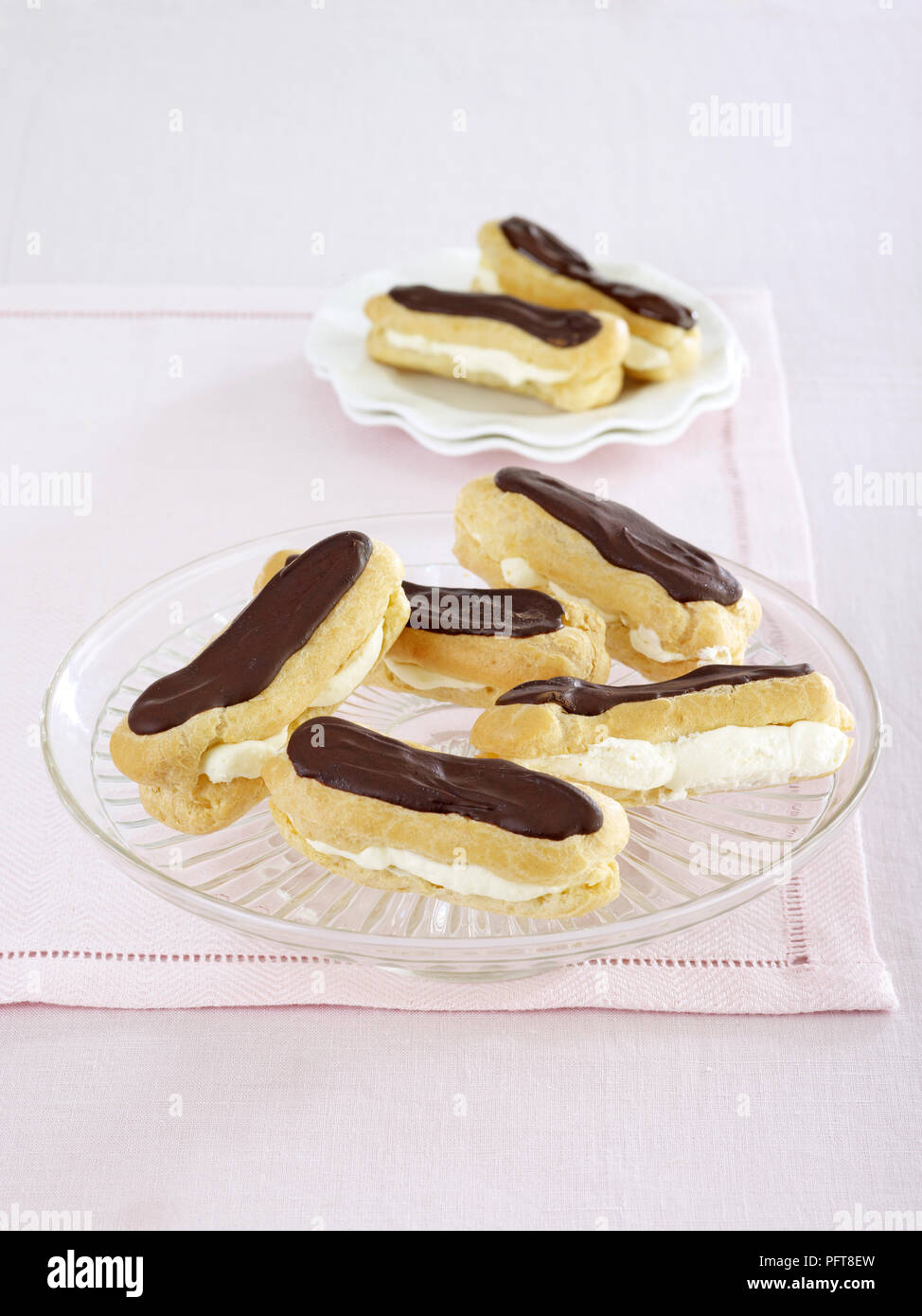 Chocolate and freshly whipped cream eclairs served on glass plate and ...