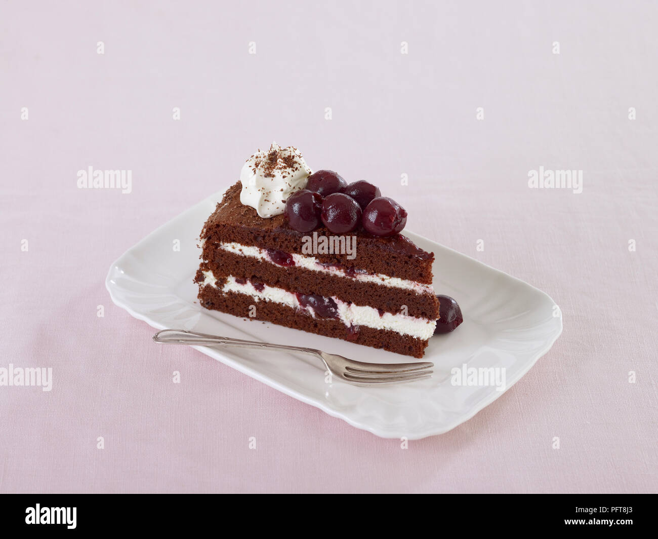 Slice of Black Forest gateau on white plate with dessert fork Stock ...