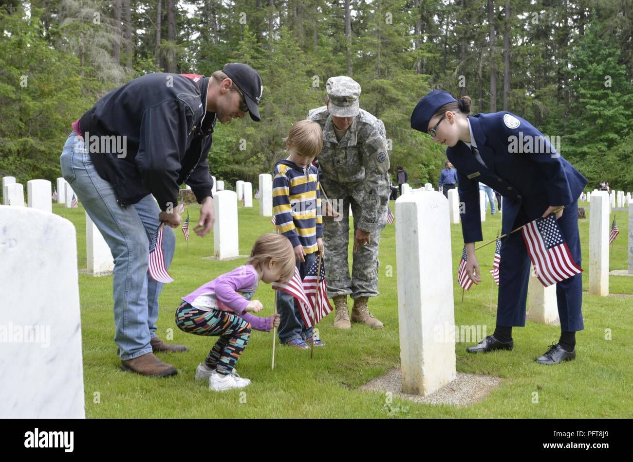 Cassidy Miller, 3, places a flag next to a tombstone at the Camp Lewis ...