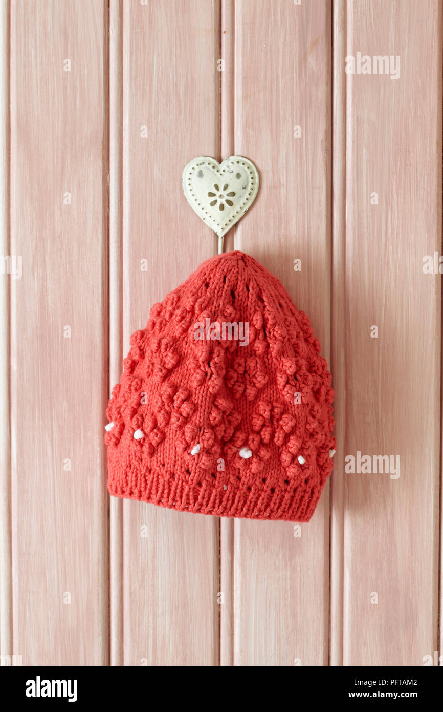 Red knitted beanie hat hanging on hook Stock Photo - Alamy