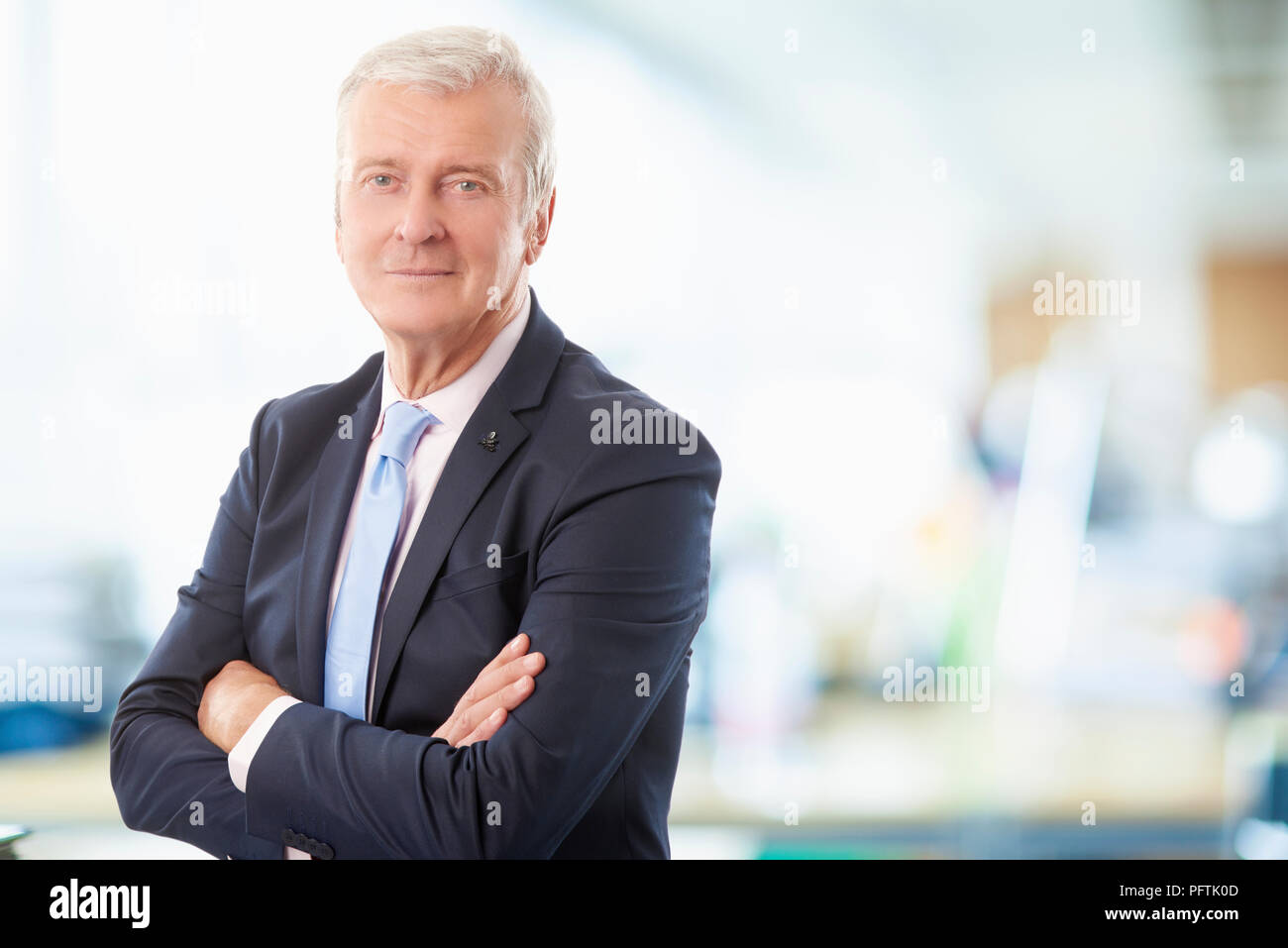 Portrait of a senior financial advisor standing with arms crossed at ...