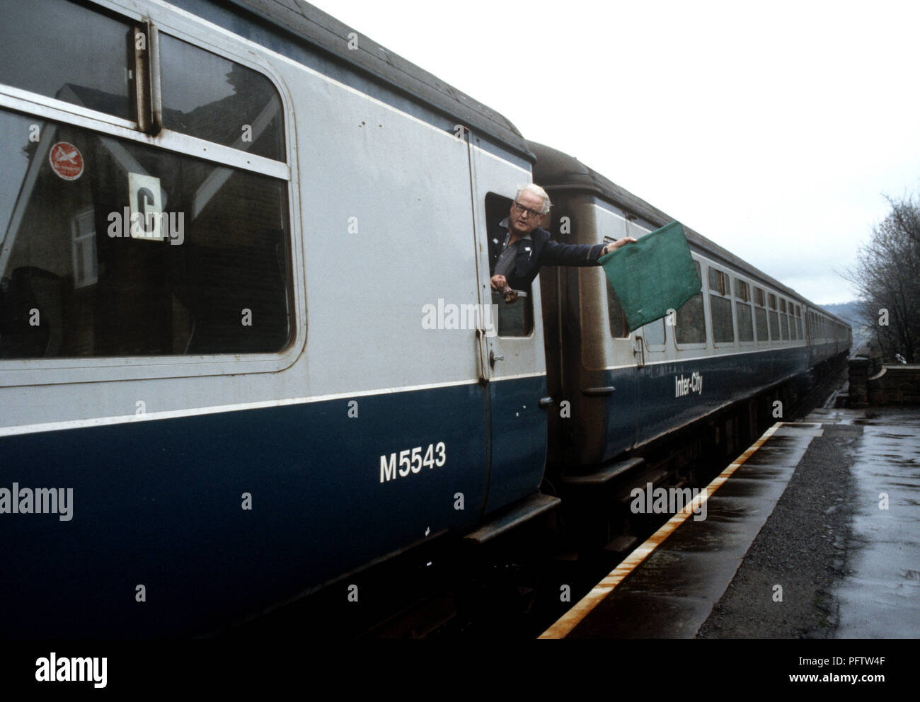 British Rail guard waving green flag to go for diesel passenger train ...