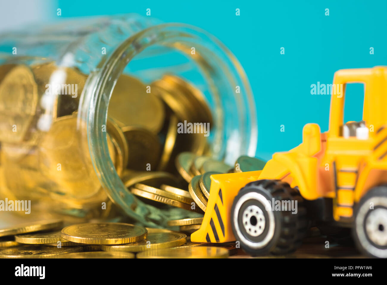 Mini bulldozer truck loading stack coin with pile of gold coin to glass ...