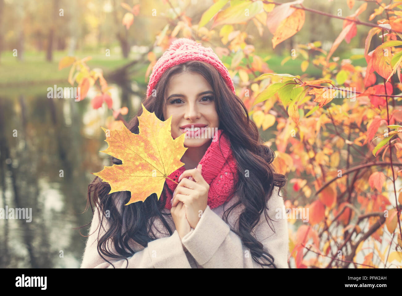 Autumn woman with bright maple leaf outdoors. Beautiful brunette girl ...