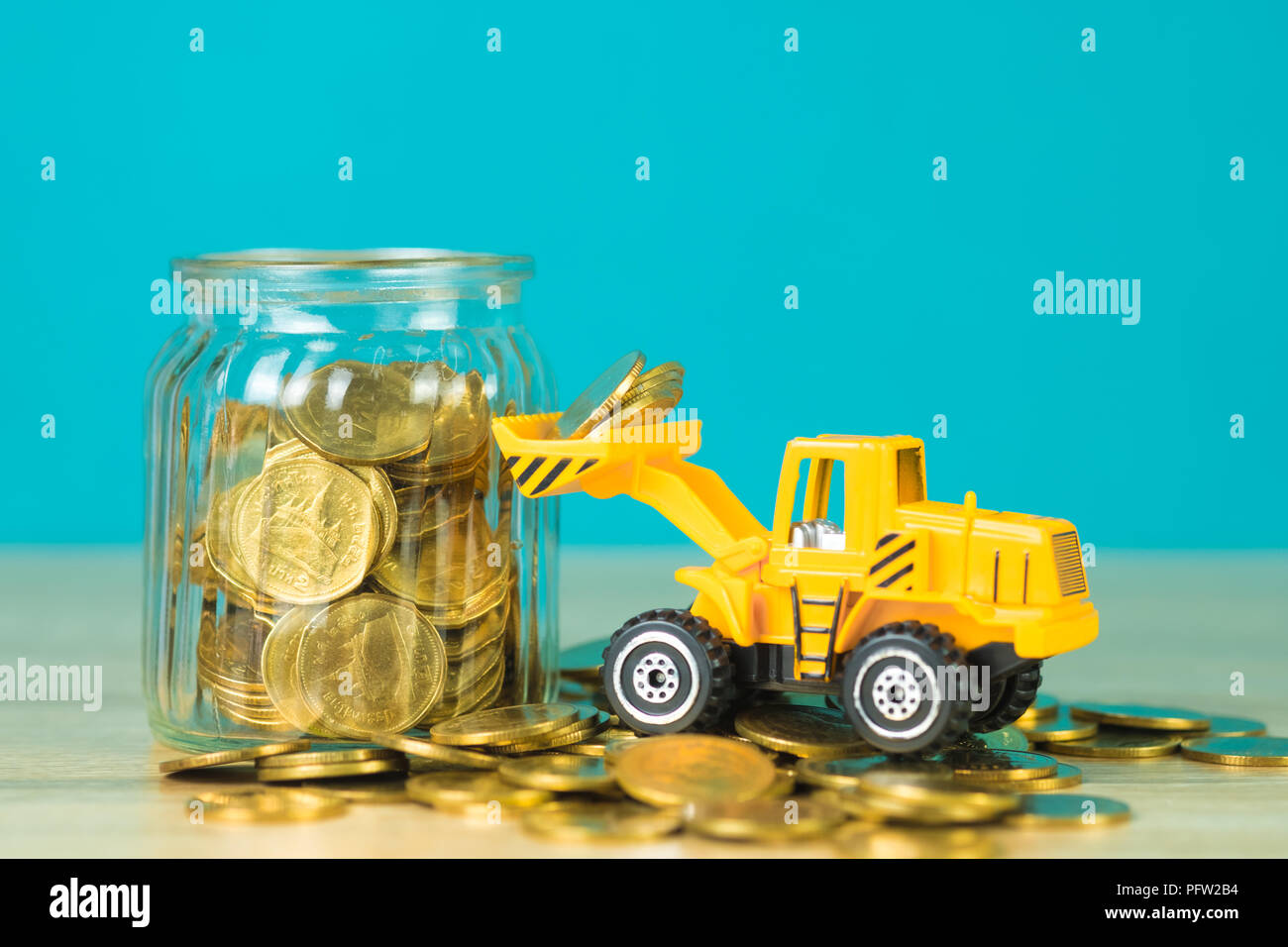 Mini bulldozer truck loading stack coin with pile of gold coin to glass ...