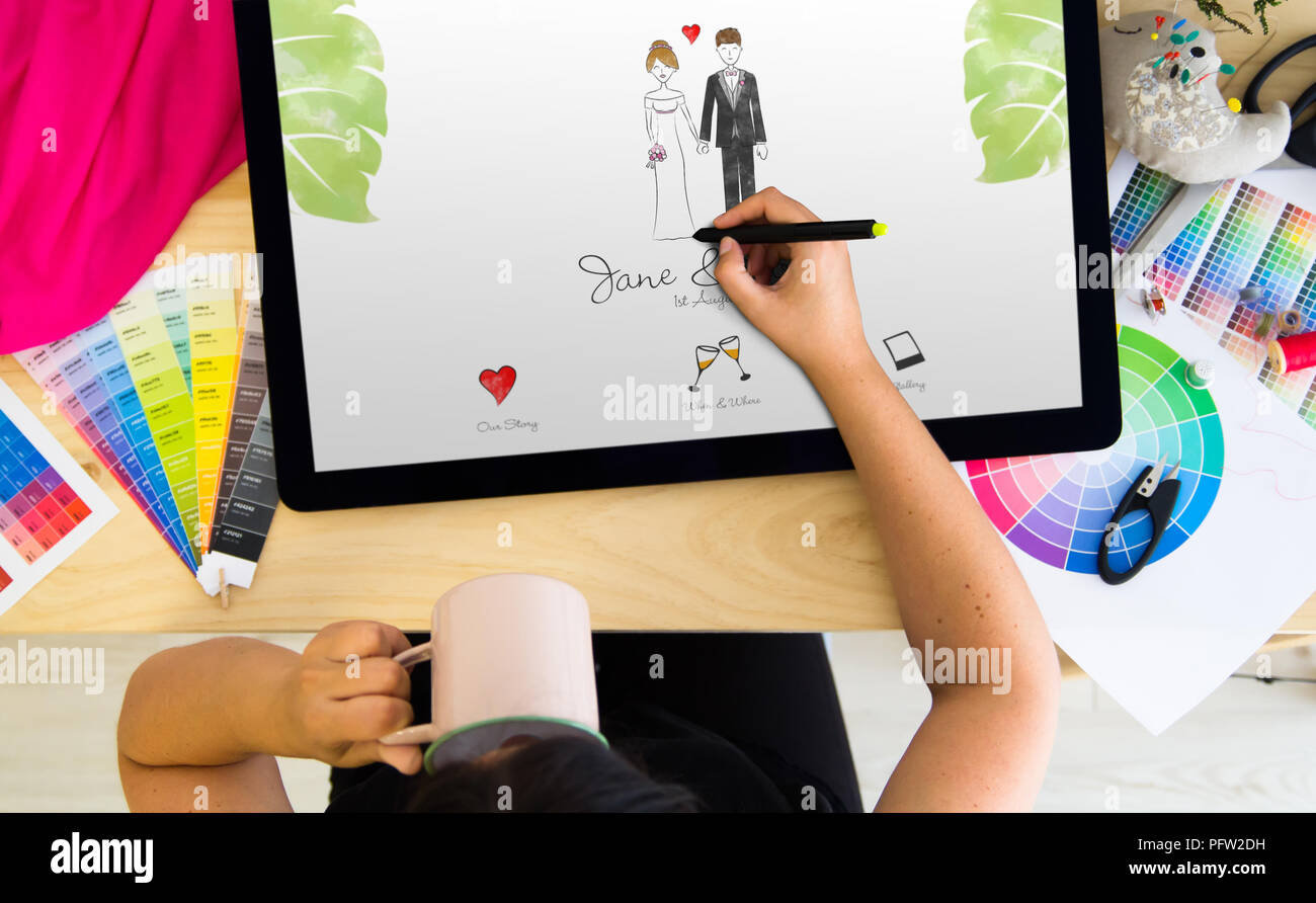 Designer working on wedding invitation with a tablet and a pen. All ...