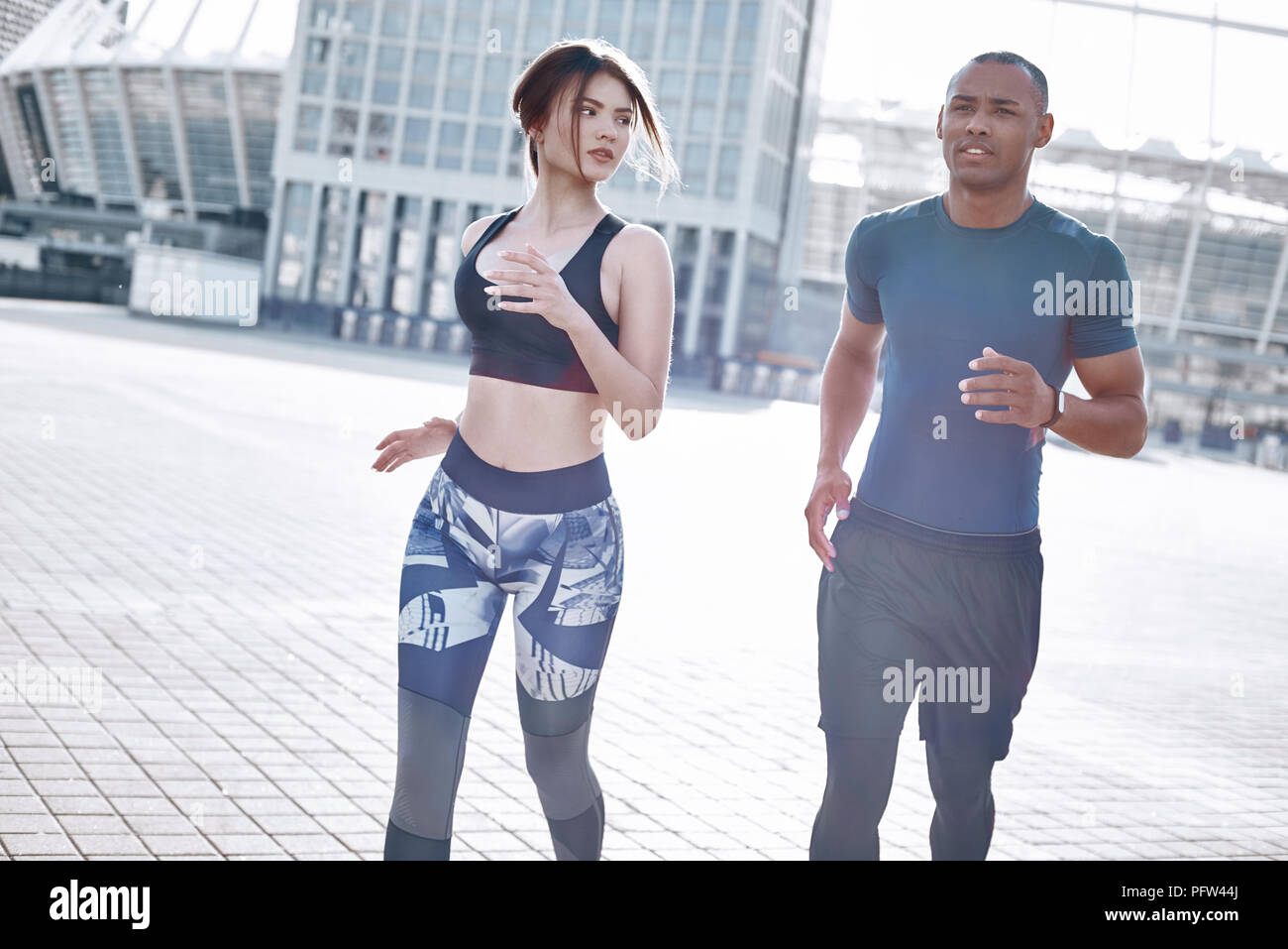 Out for a run. Full length of young couple in sport clothing running ...