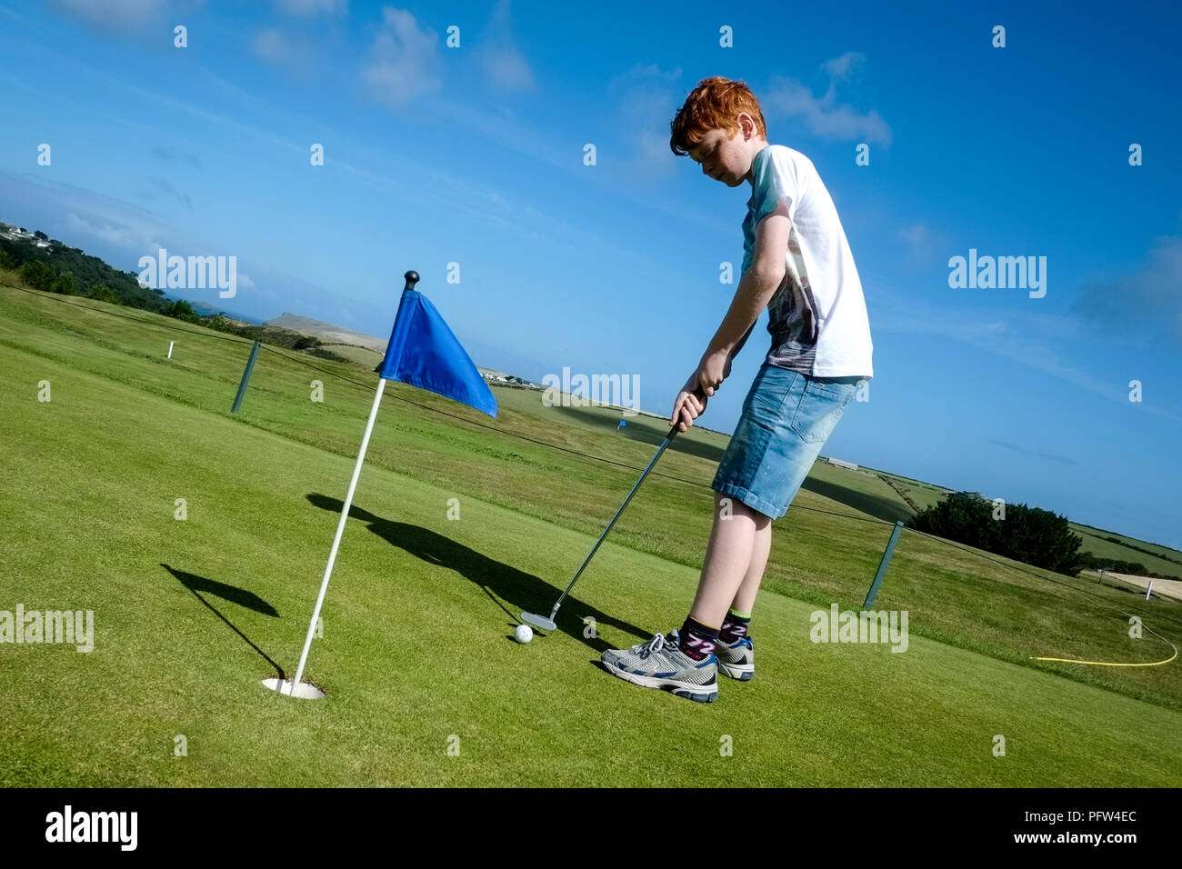 Young boy teenager practicing putting a golf ball on a green.Cornwall ...
