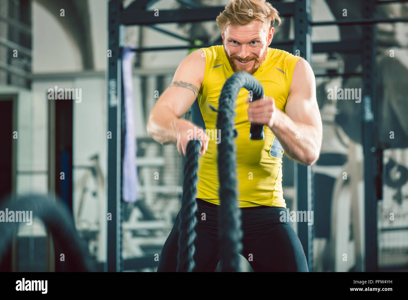 Handsome bodybuilder exercising with battle ropes during functional ...