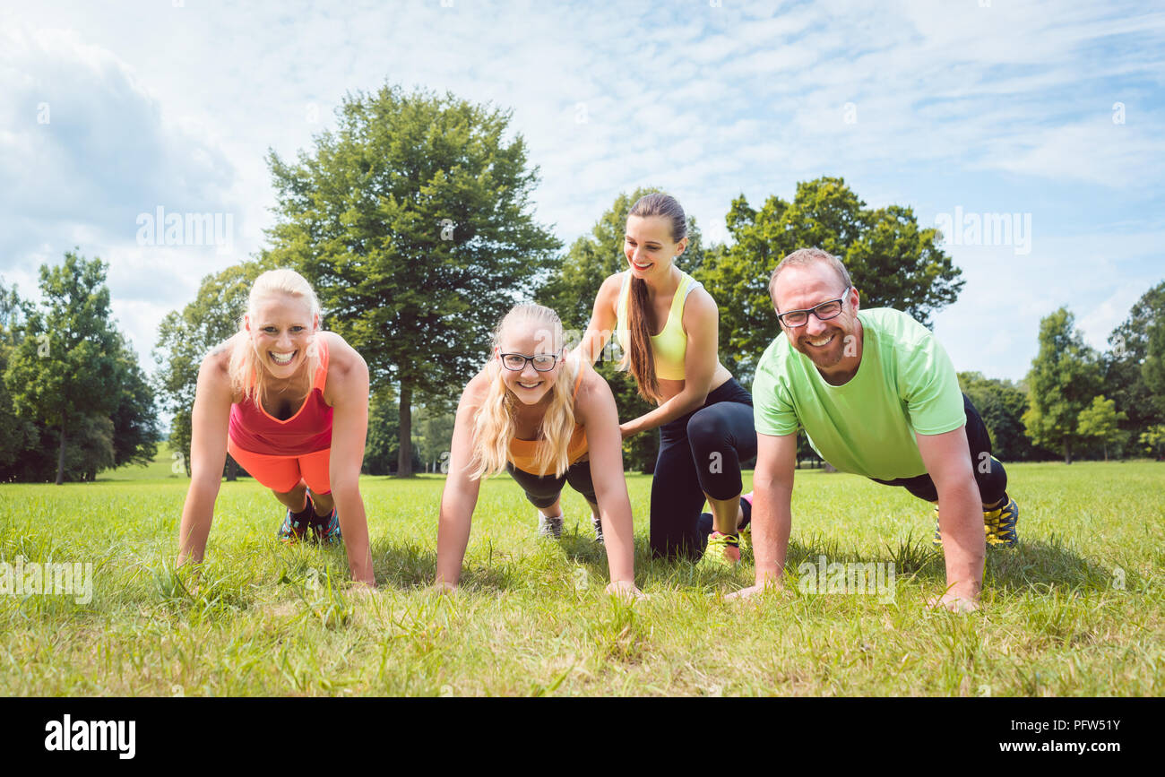 Family doing push-ups in nature under guidance by a fitness coach Stock ...