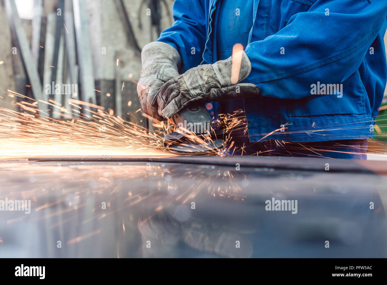 Worker in metal factory grinding workpiece with sparks flying Stock ...