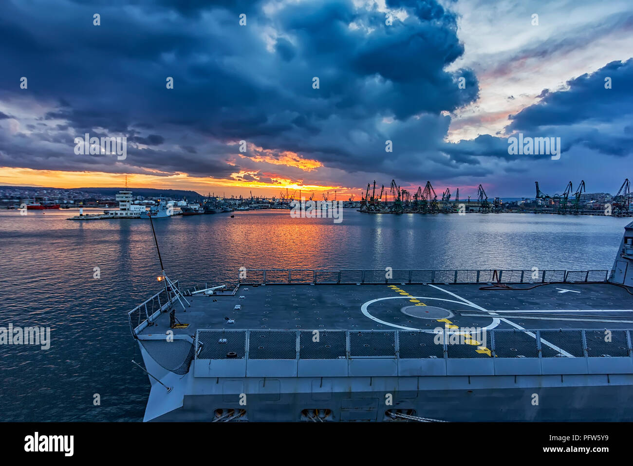 Part of the frigate, a helicopter landing at sunset in the harbor ...