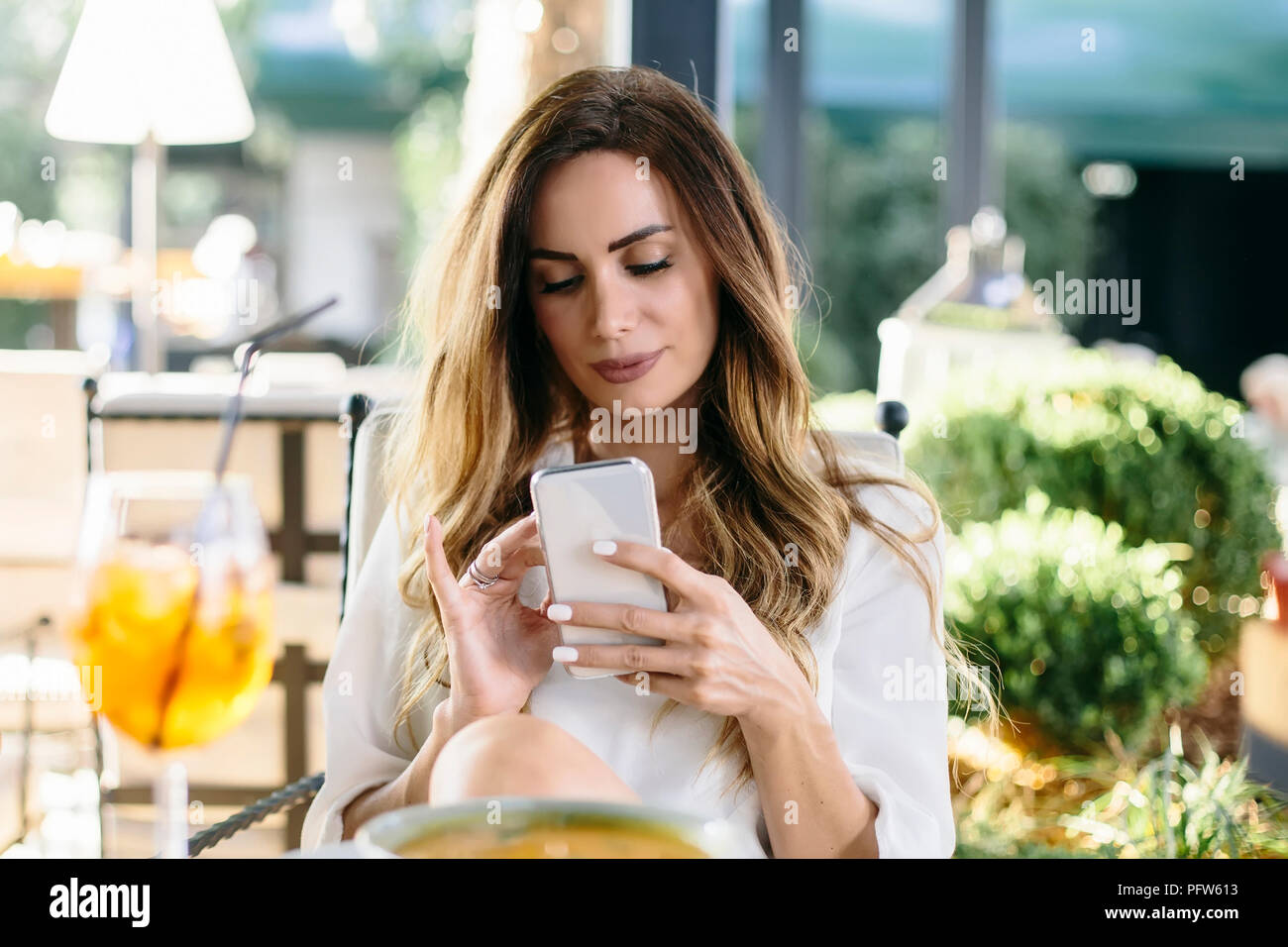 Portrait of attractive young woman sitting in restaurant and using ...