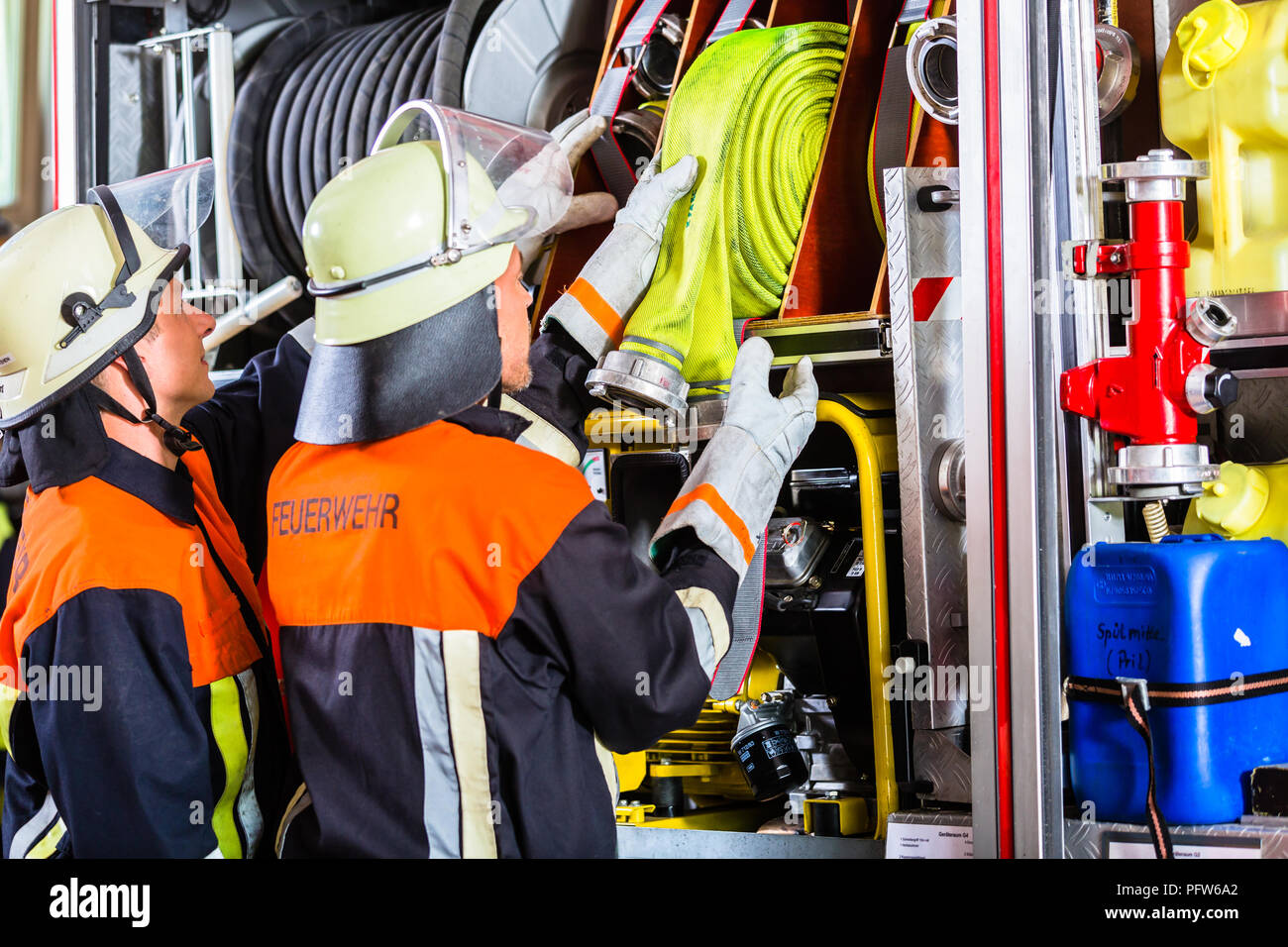 Fire fighters loading hoses into operations vehicle Stock Photo - Alamy
