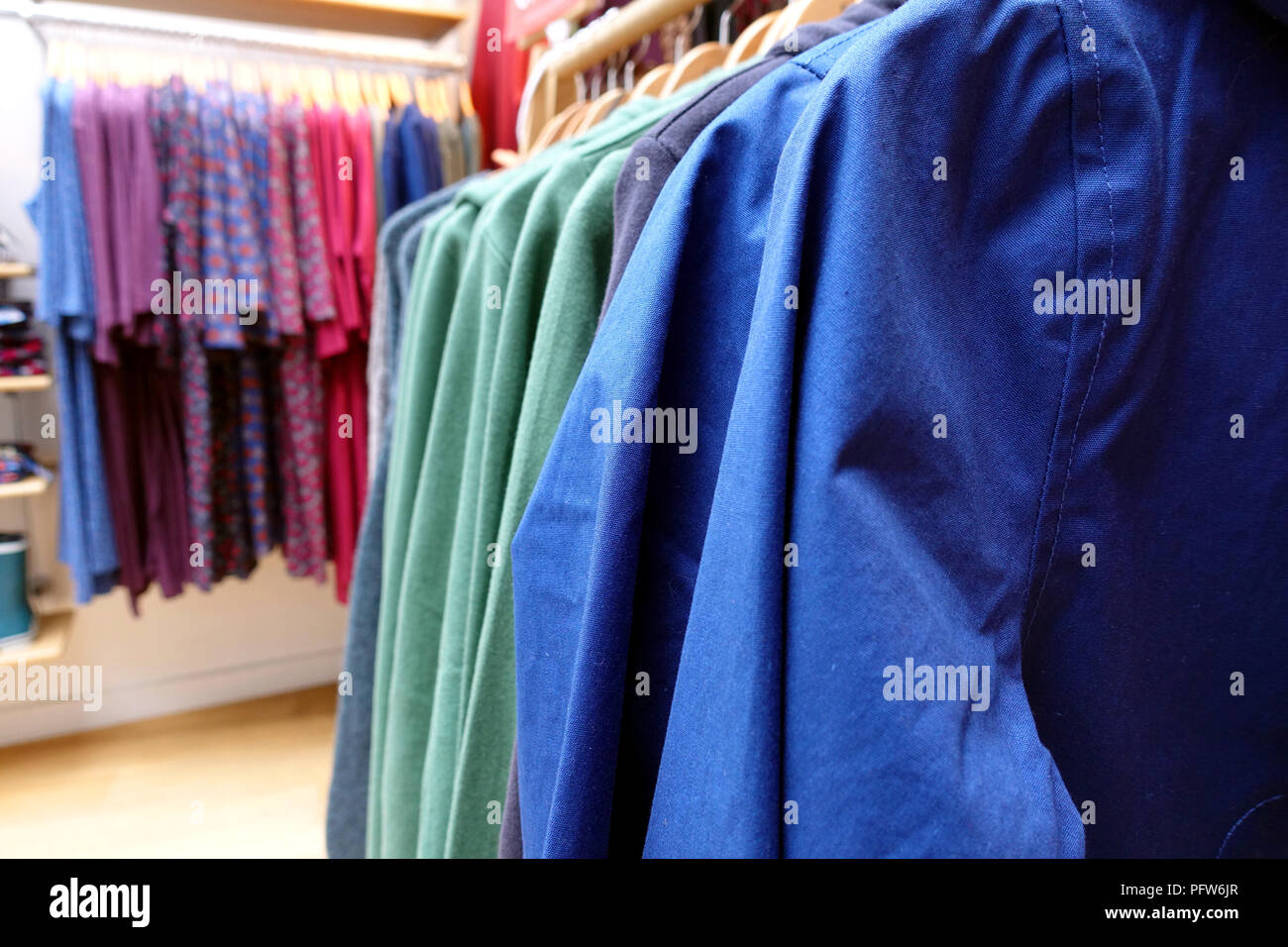 Shallow focus close up of a rack of blue and green clothes in a ...