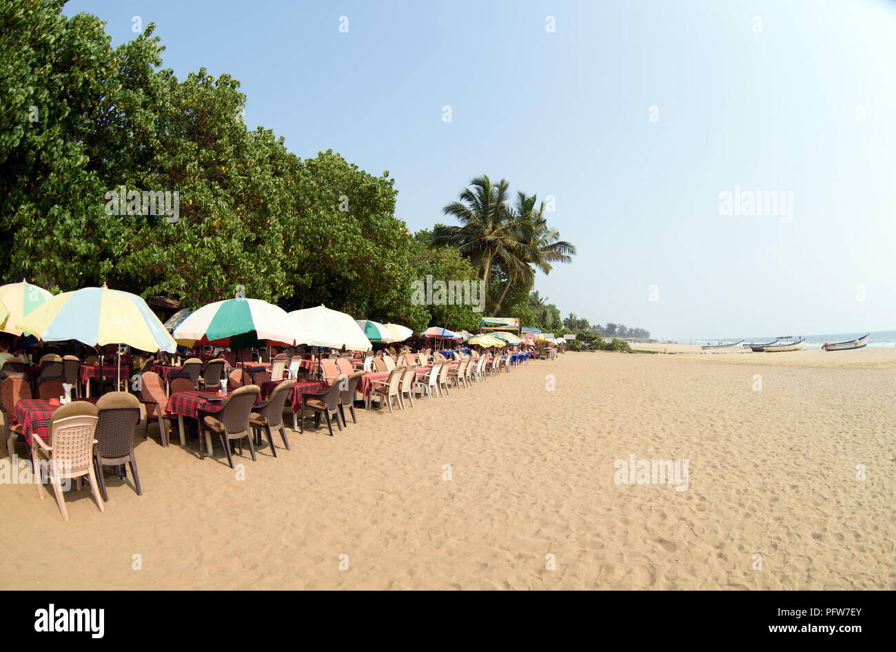 Summer outdoor cafe with sun umbrellas on sand tropical beach in goa ...