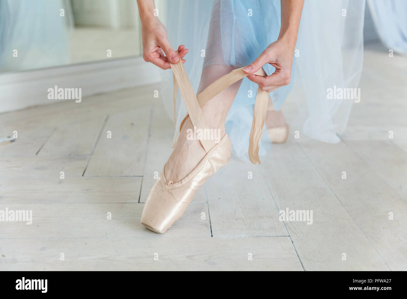 Beautiful legs of young ballerina who puts on pointe shoes at white ...