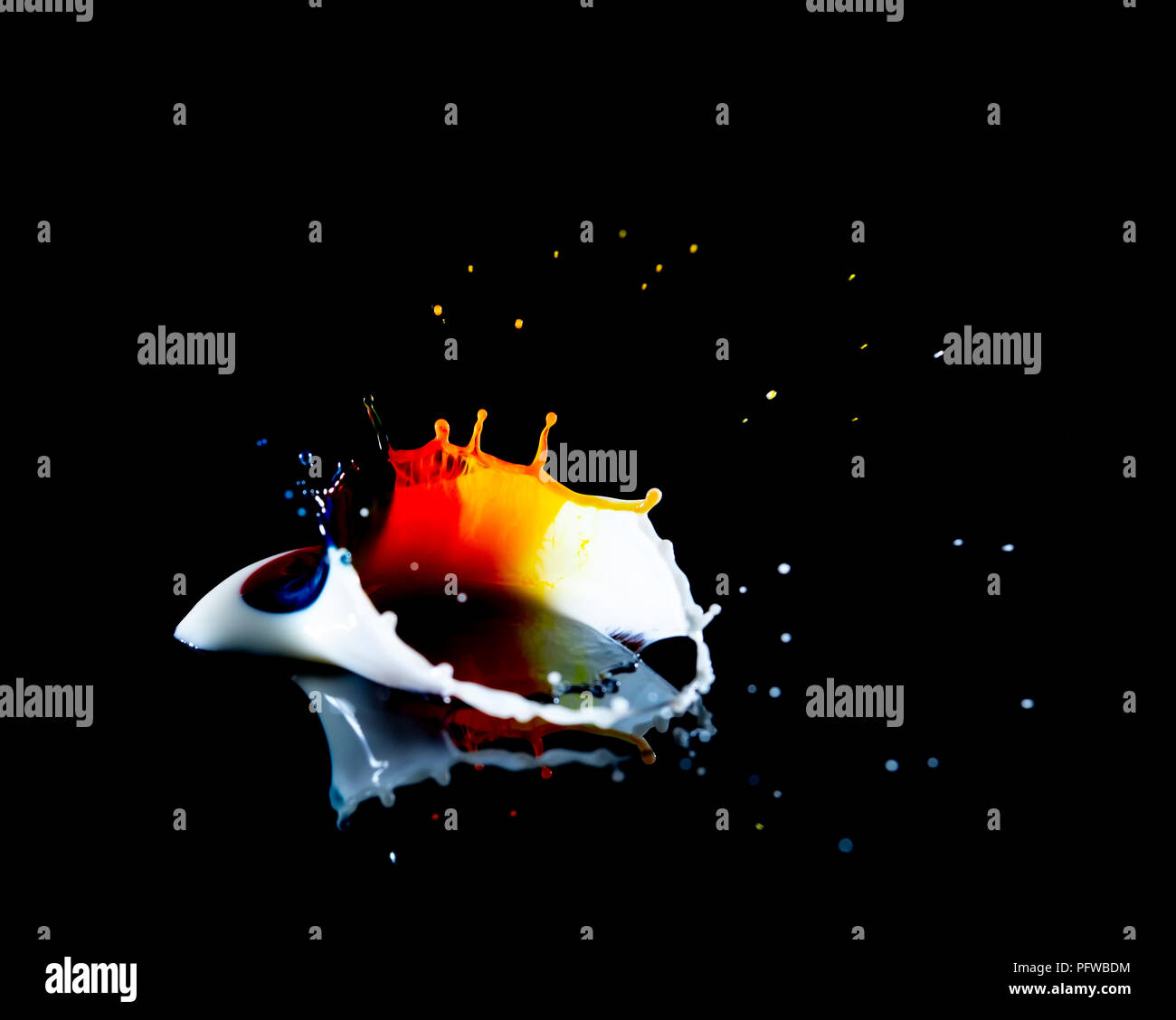 Stop action view of water drop splashing down on multicolored liquid ...