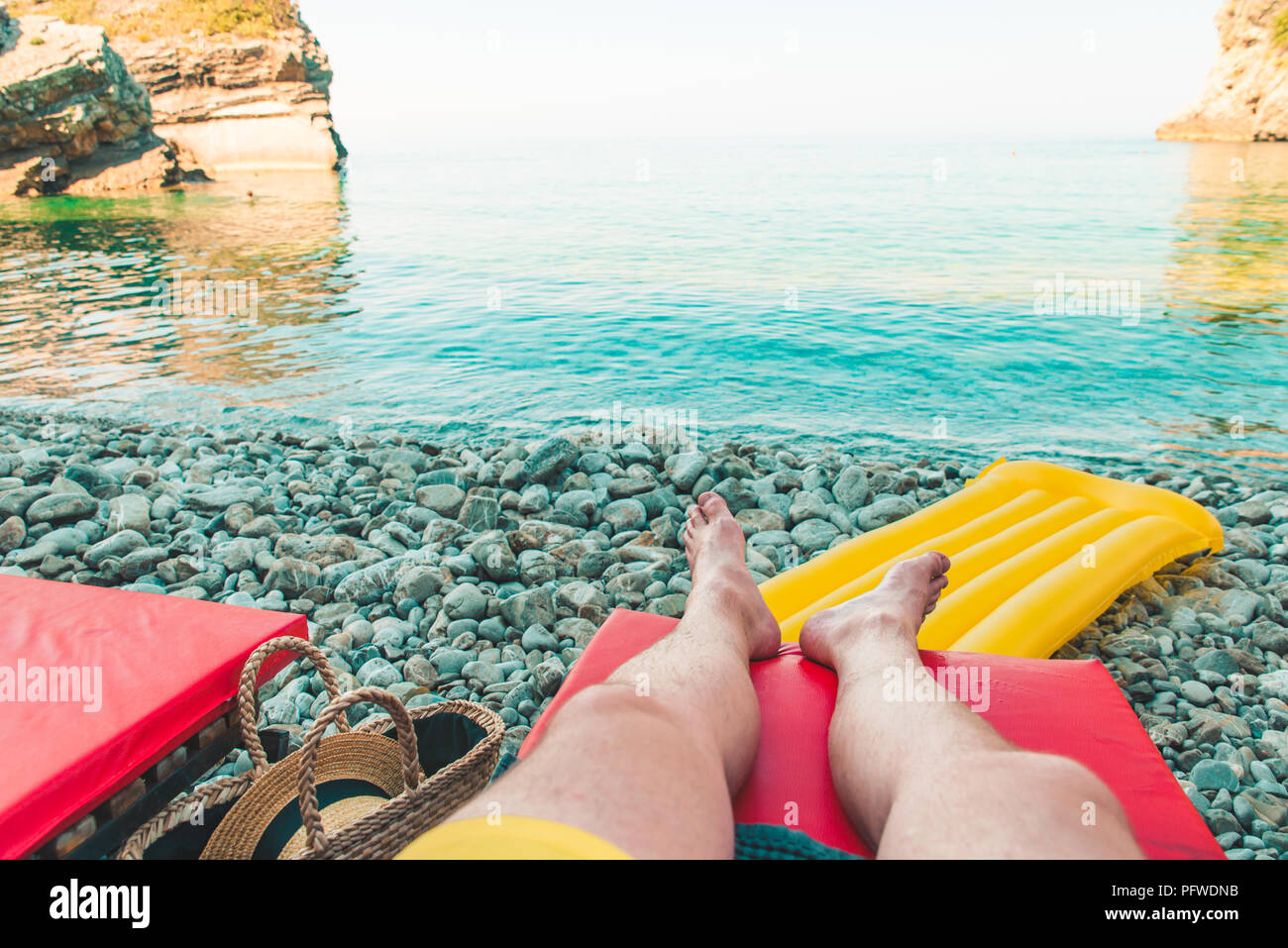 man laying at sun loungers with beautiful view of sea with rocks ...