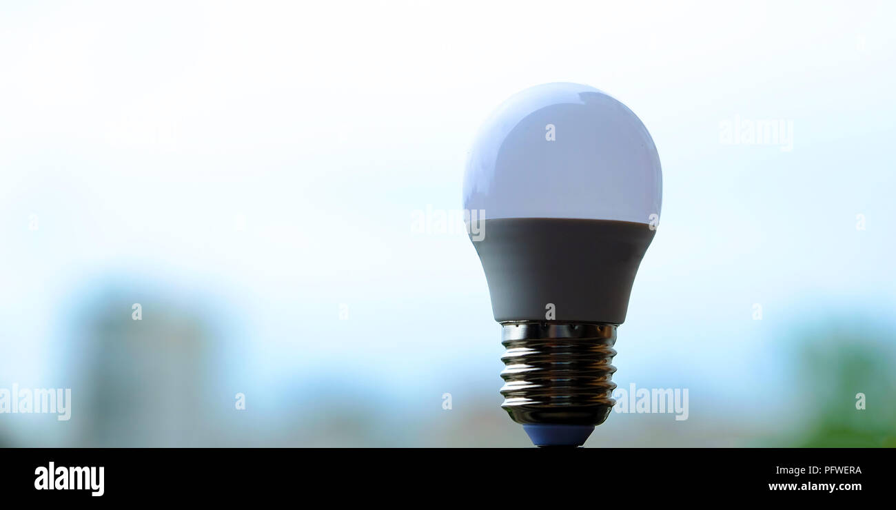 A small light bulb stands on a light background Stock Photo - Alamy