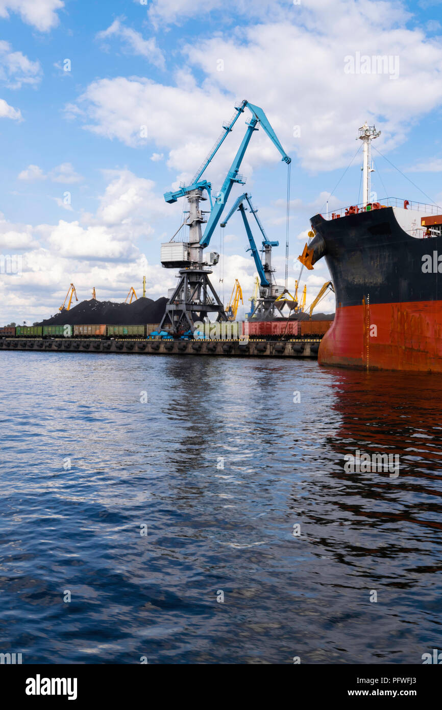 Large red cargo ship loading with a coal in the port, terminal, crane ...