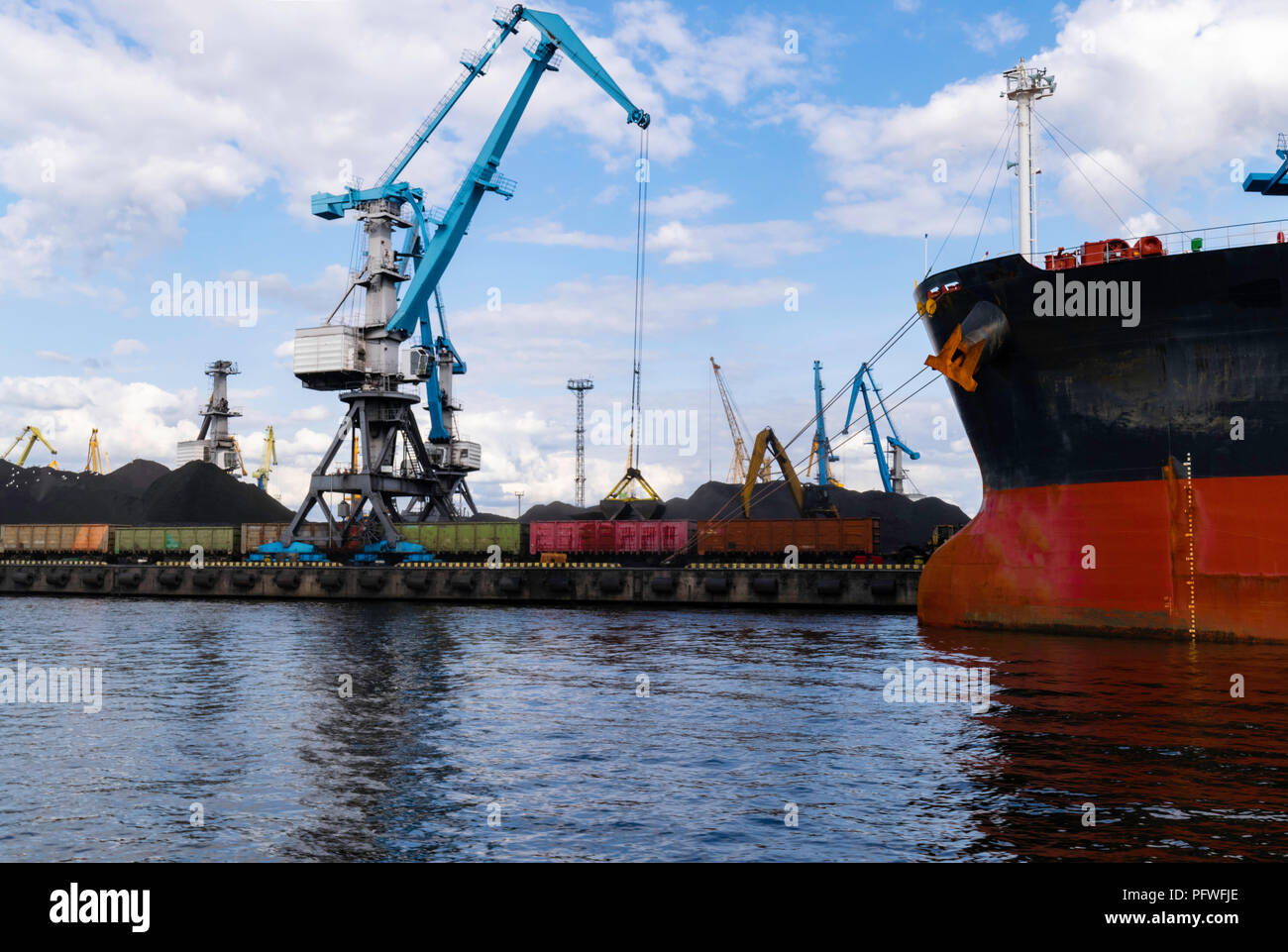 Large red cargo ship loading with a coal in the port, terminal, crane ...