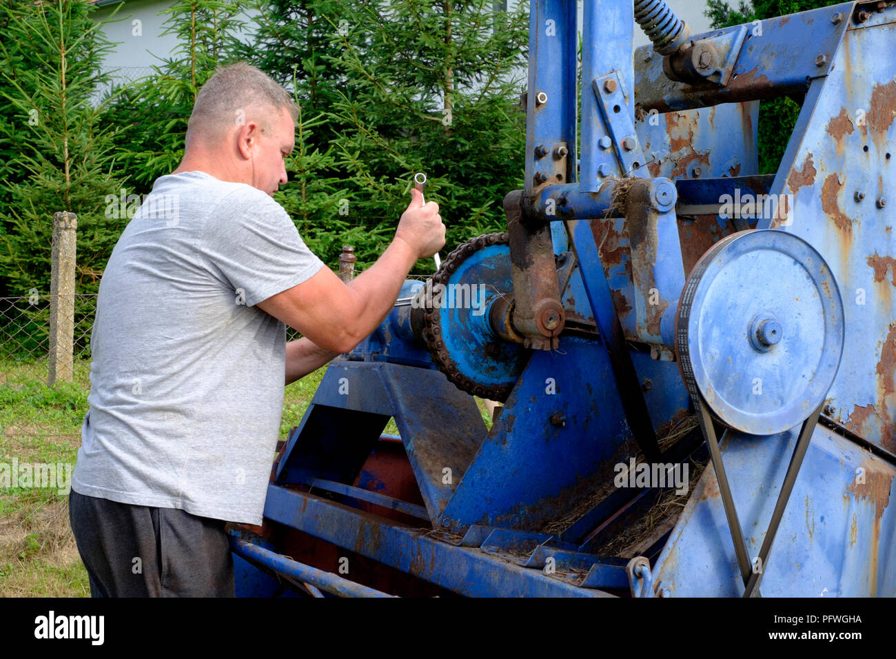 man working on partially restored and renovated baling machine being ...