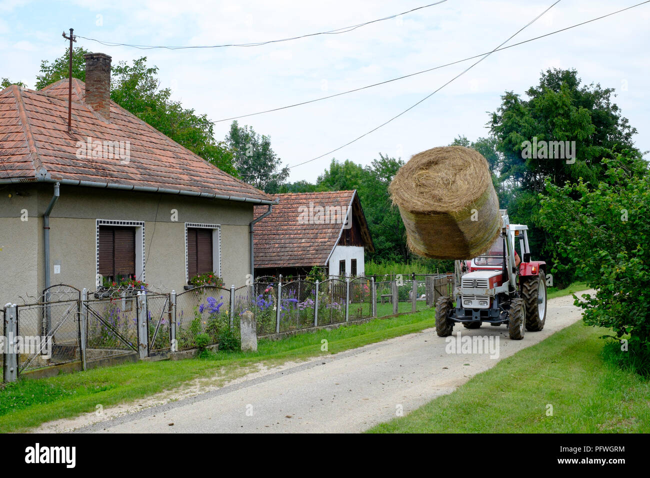 steyr 650 tractor driving through rural hamlet on country lane with ...