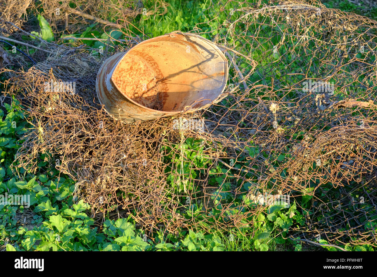 rusty pail discarded on top of rusting wire fencing prior to scrapping ...