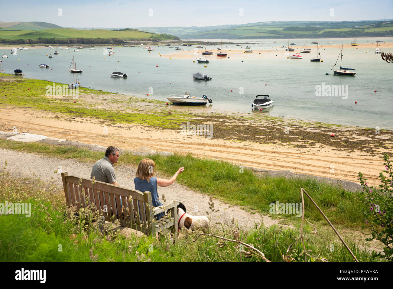 UK, Cornwall, Rock, couple sat on waterfront bench beside River Camel ...