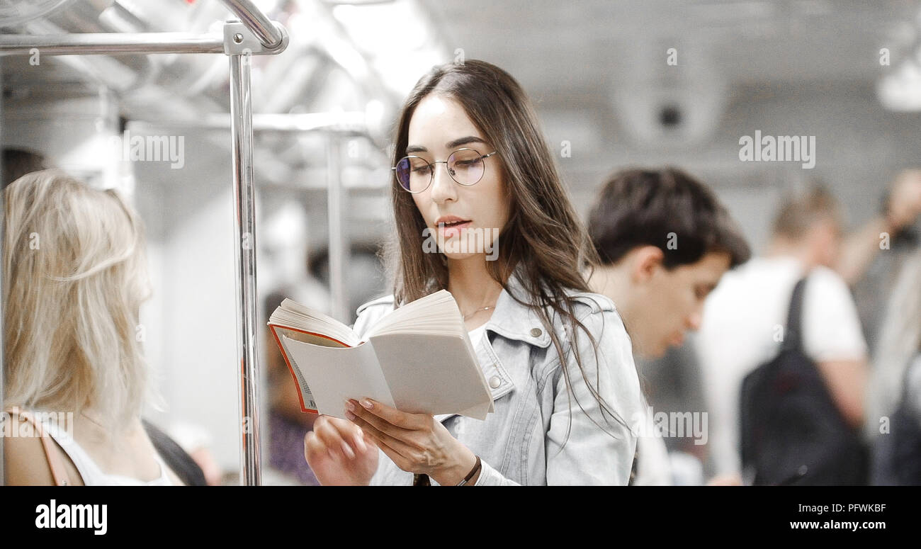 Girl reading a book on the subway in the middle of the crowd Stock ...