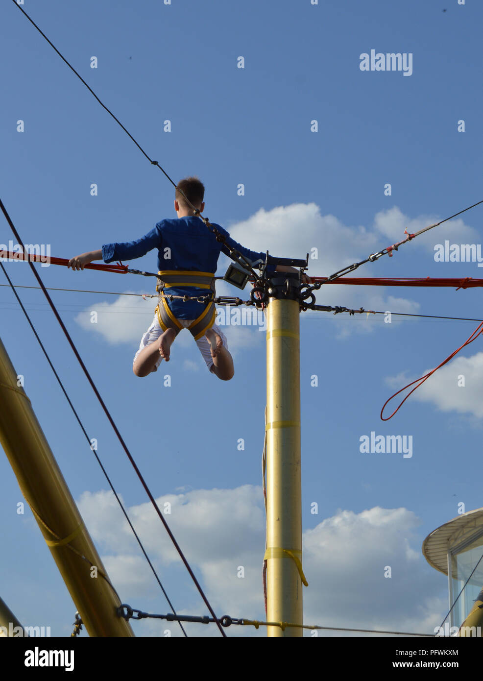 The boy gladly jumps on the bungee in the amusement Park against the ...
