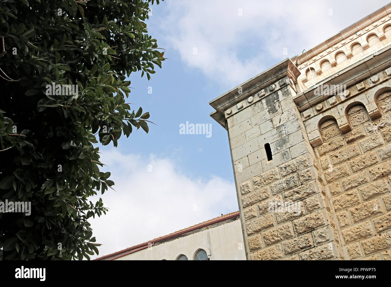 Wall of Joseph Church, foliage of tree and blue sky in Nazareth, Israel ...