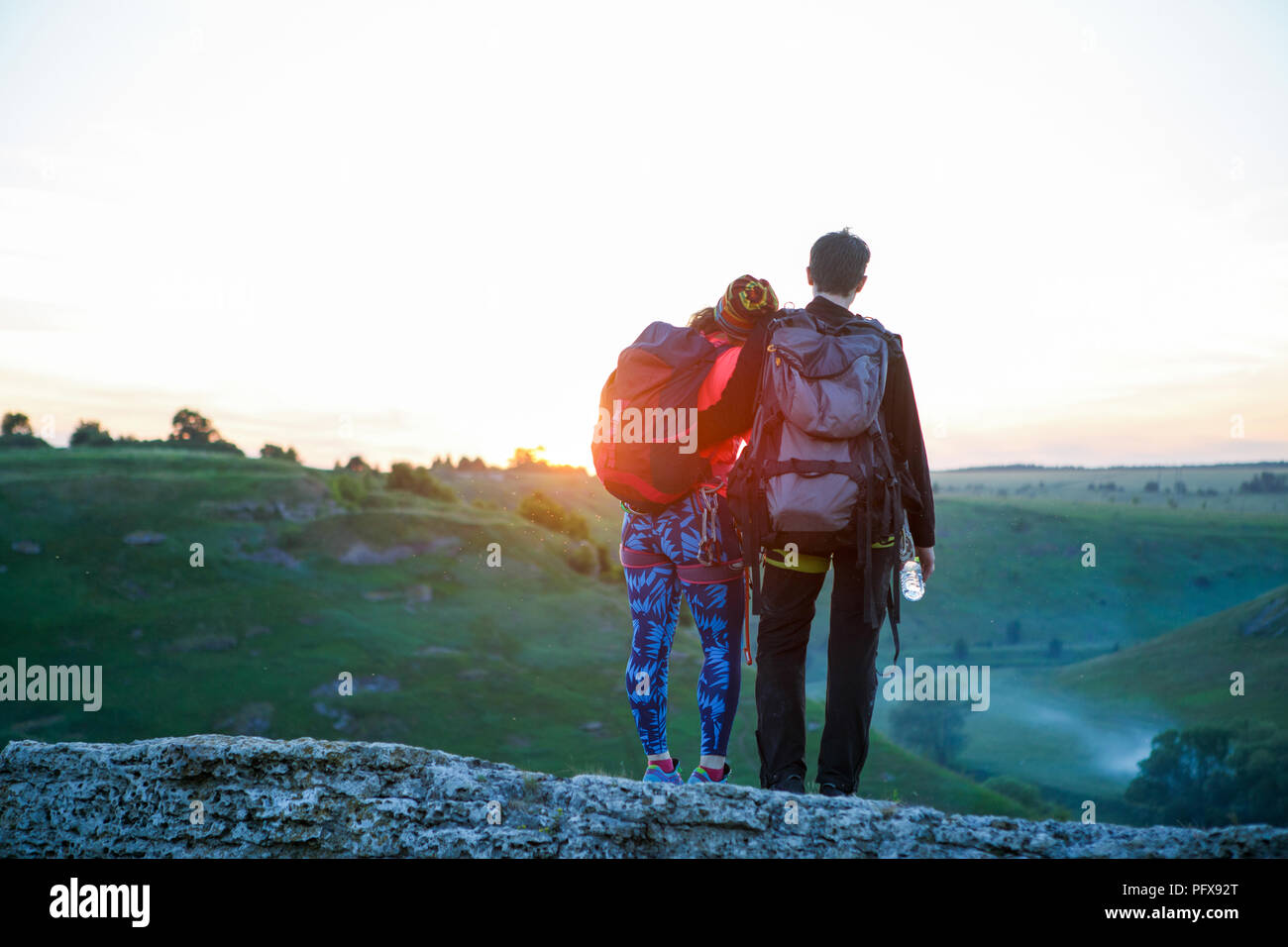 Photo from back of hugging man and tourist woman with backpacks on ...