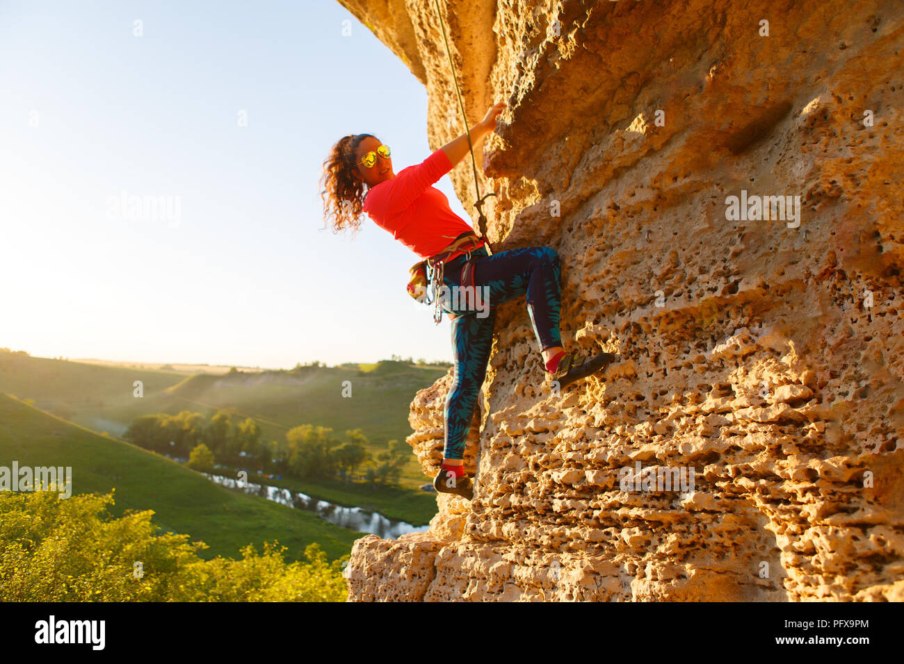 Picture of curly-haired female tourist clambering over rock Stock Photo ...