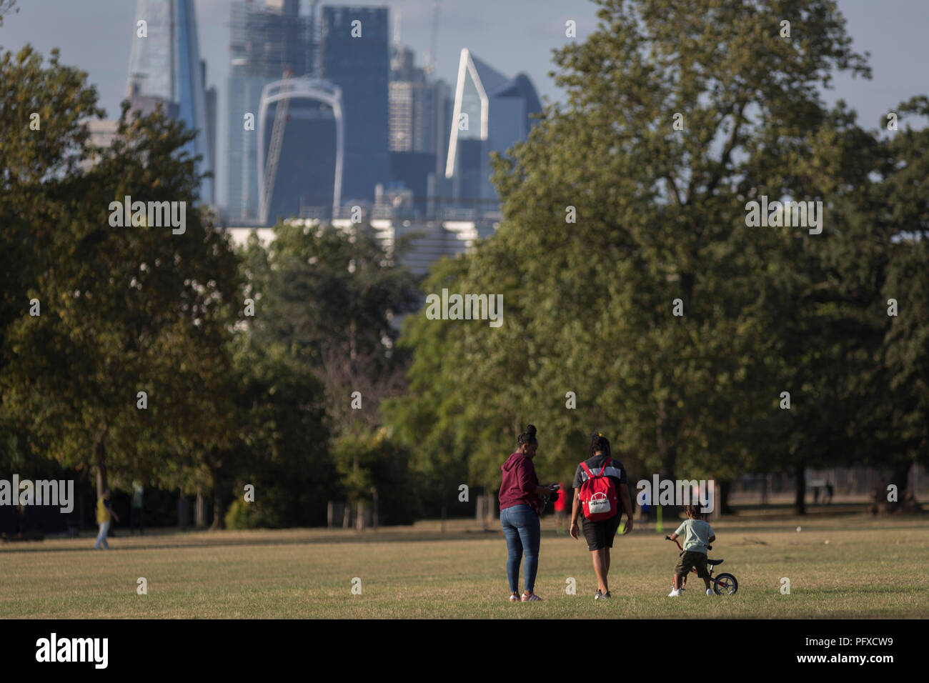 A family walk through Ruskin Park with the skyline of the City of ...