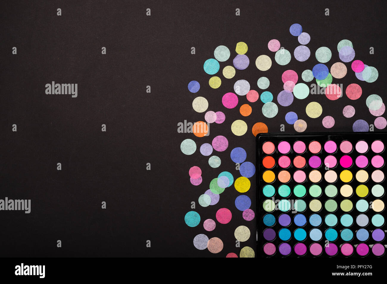 Make-up eyeshadow palette with confetti scattered on black background ...