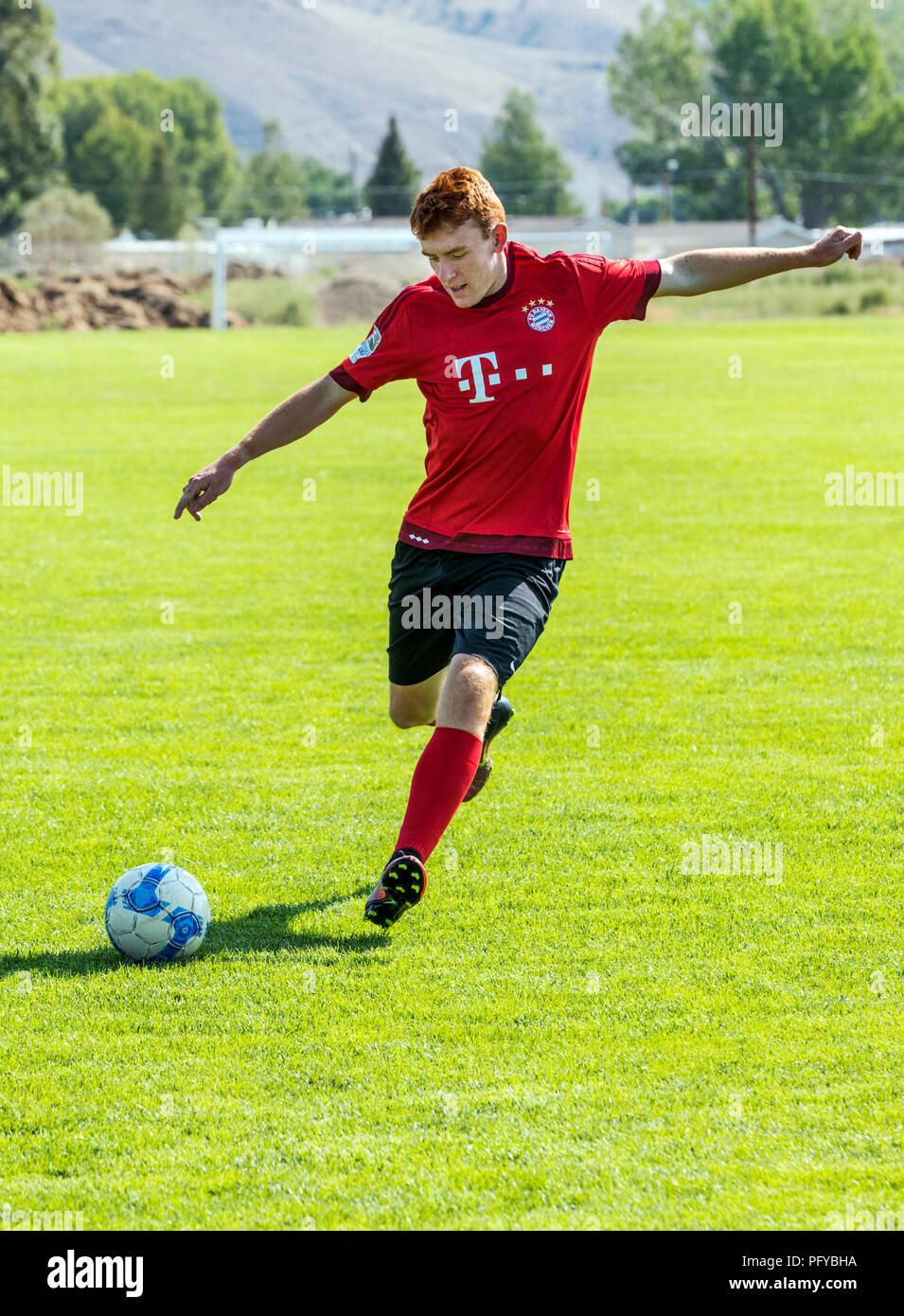Teenage boy kicking soccer ball; playing fields; Ben Oswald Park ...