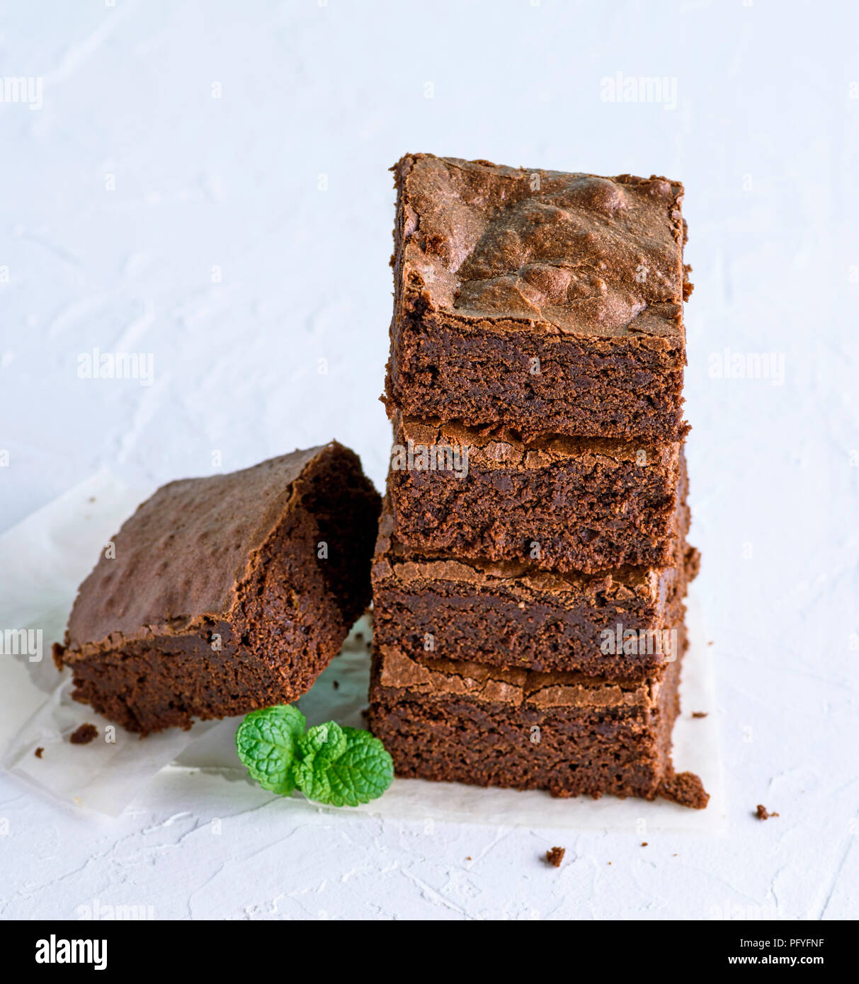 baked square pieces of brownies stacked in a pile on a white background ...