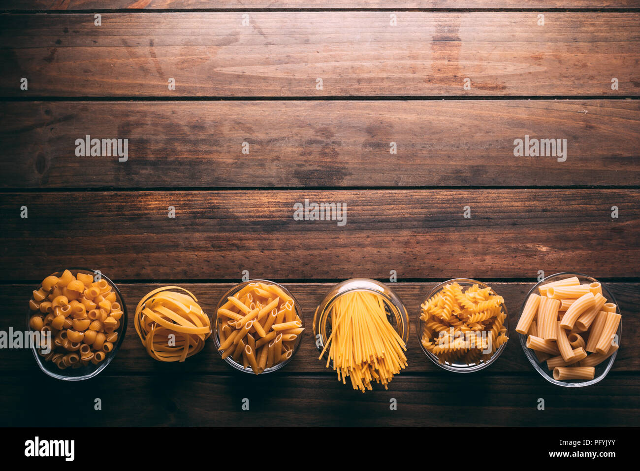 Top view of a rustic wooden table full of different types of pasta ...