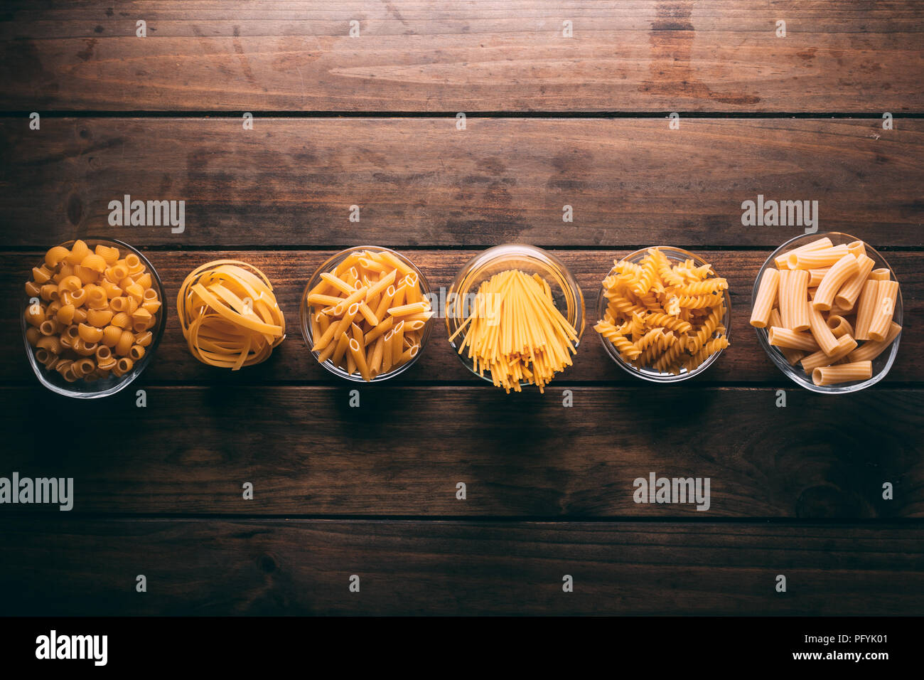 Top view of a rustic wooden table full of different types of pasta ...
