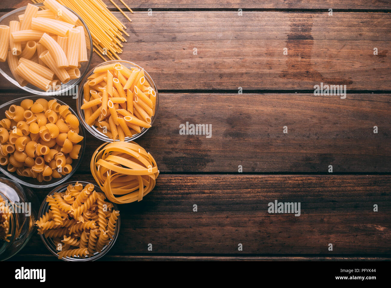 Top view of a rustic wooden table full of different types of pasta ...