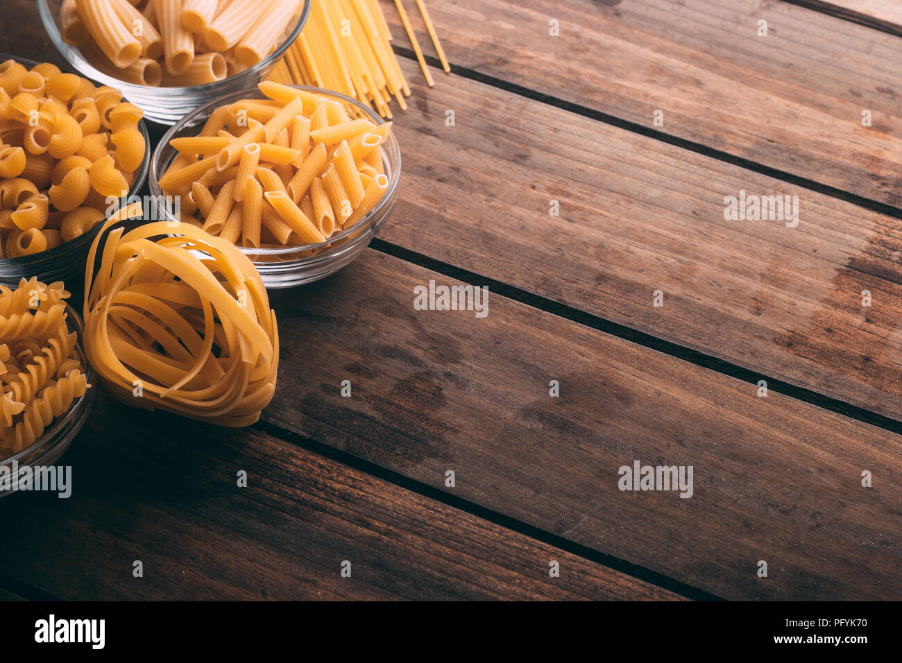 Top view of a rustic wooden table full of different types of pasta ...