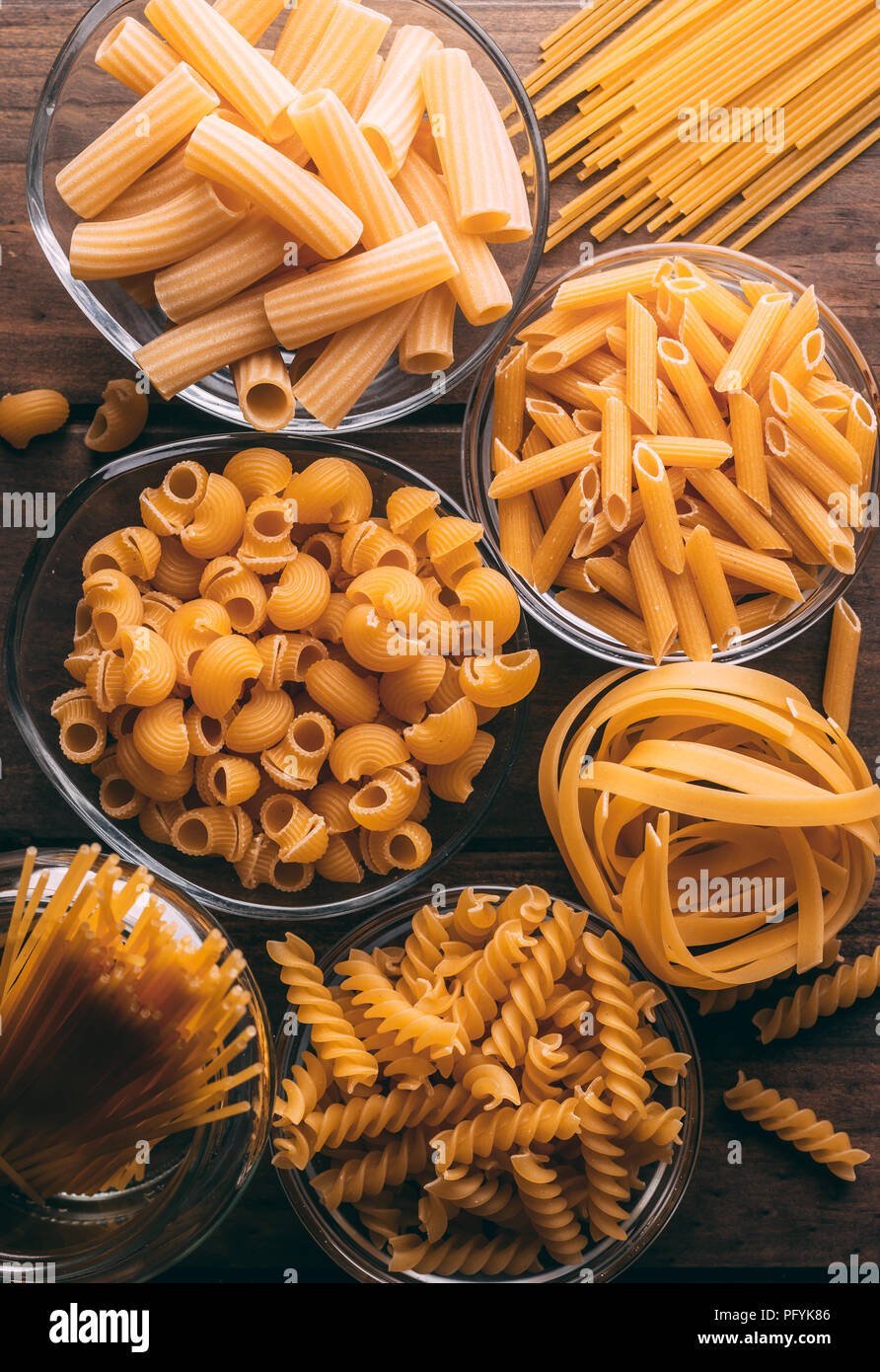 Top view of a rustic wooden table full of different types of pasta ...